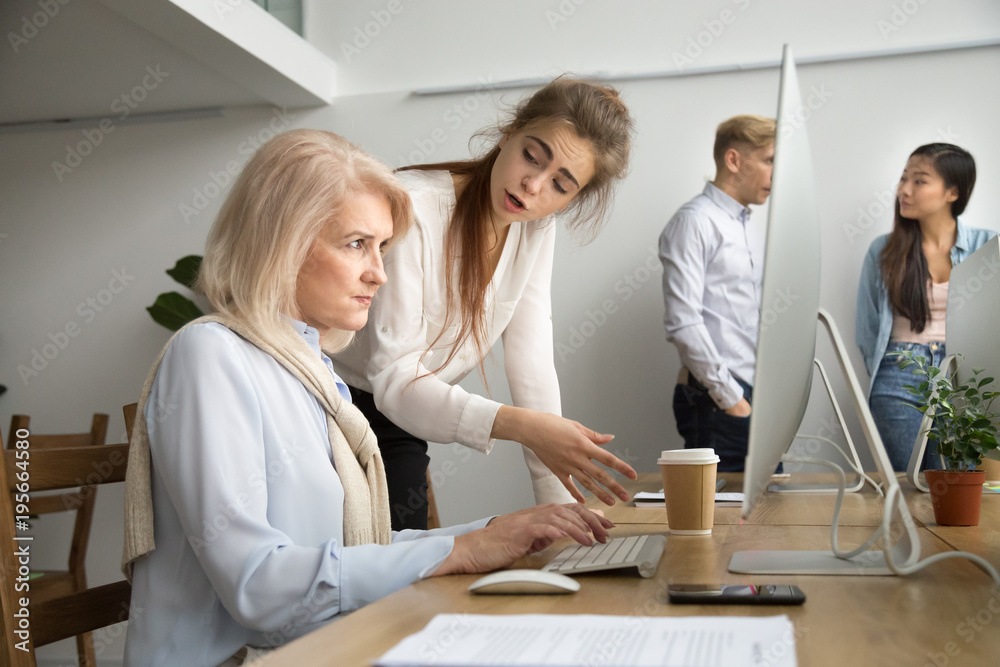 Young team leader correcting offended senior employee working on ...