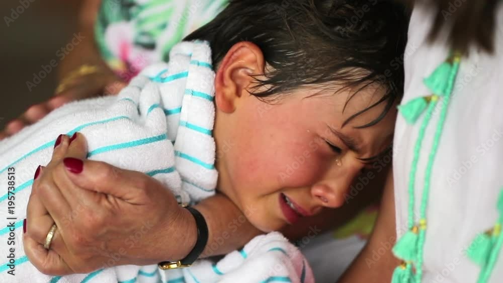 Crying child being consoled by grand-mother arms. Young boy crying and ...