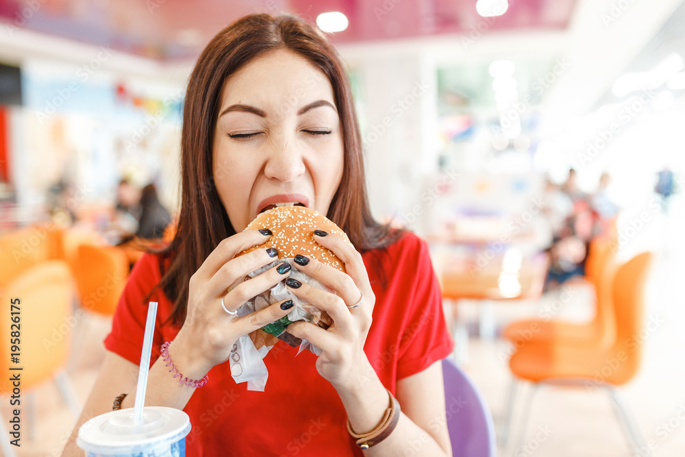 Healthy young woman biting her hamburger in fast food court Stock Photo ...