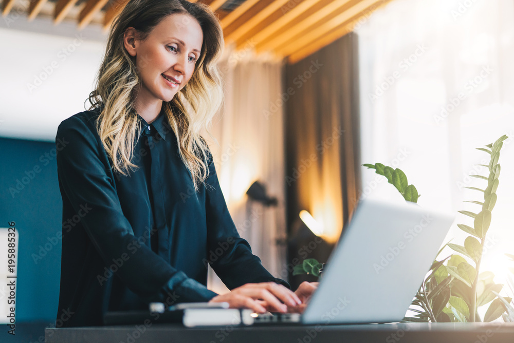 Young smiling businesswoman in black blouse is standing indoor, working ...