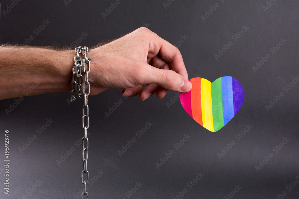 LGBT Discrimination, chained hand hold heart LGBT flag. close up ...