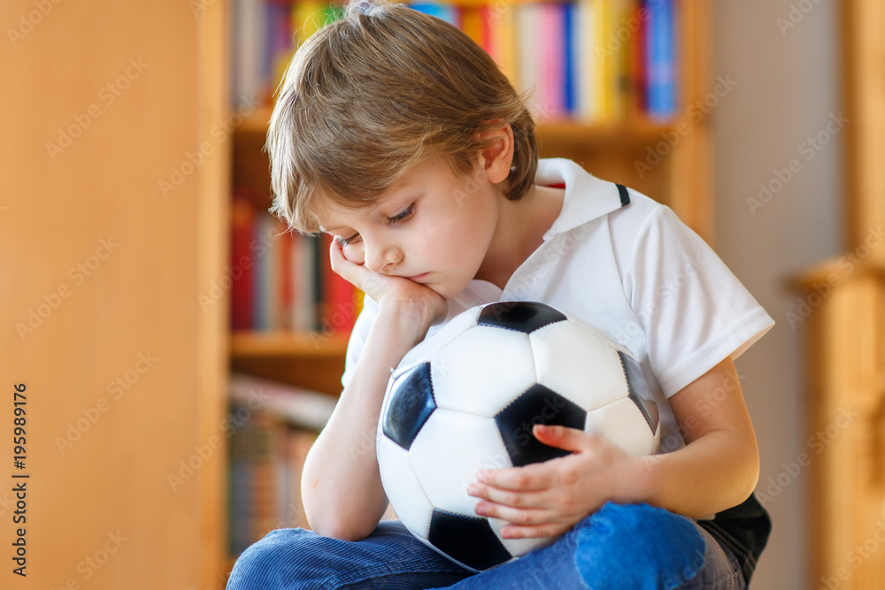 Sad and not happy little kid with football about lost football or ...