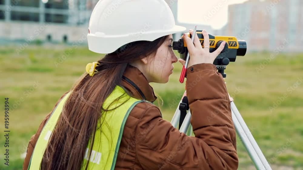 Video Stock young woman surveyor in green work clothes and helmet ...