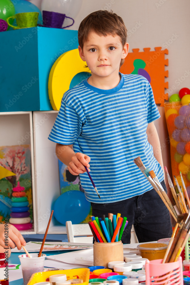 Small student boy painting in art school class. Child drawing paints on ...