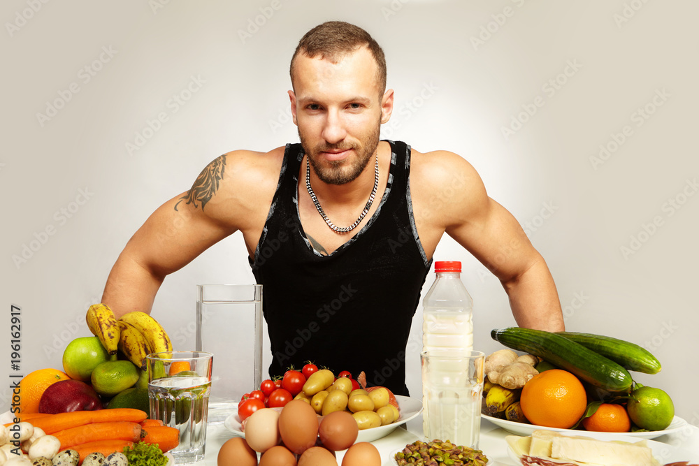 Muscle fitness man posing with his healthy food menu on plates Stock ...
