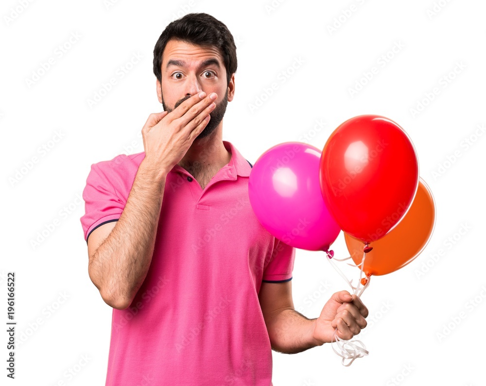 Handsome young man holding balloons and covering his mouth over ...
