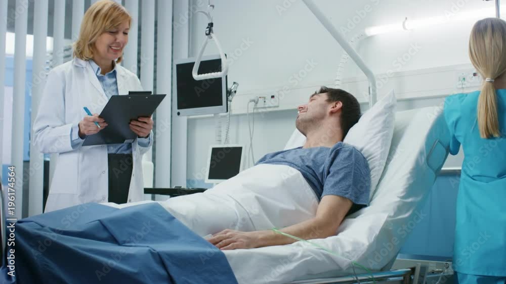 Friendly Female Doctor Visits Smiling Recovering Man who is Lying in ...