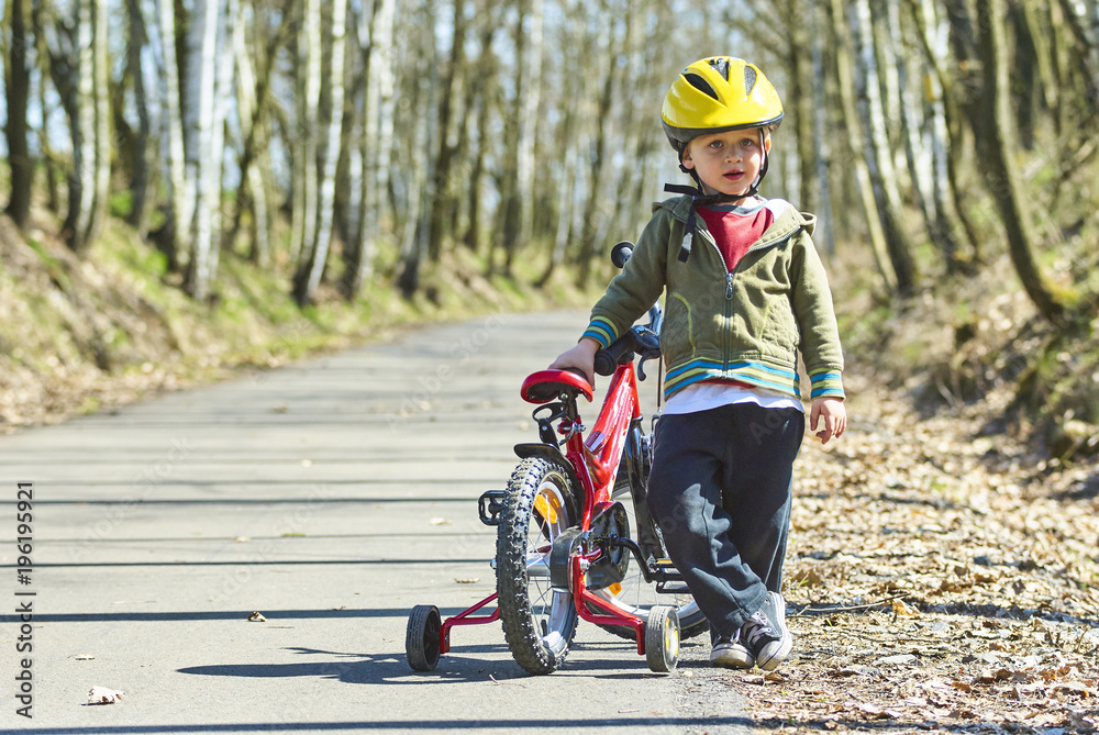 Little child boy cycling on bicycle in green park outdoor in spring. A ...