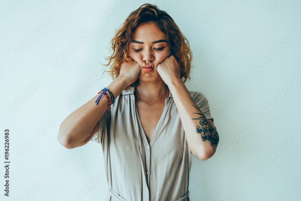Funny young woman pushing cheeks in studio Stock Photo | Adobe Stock