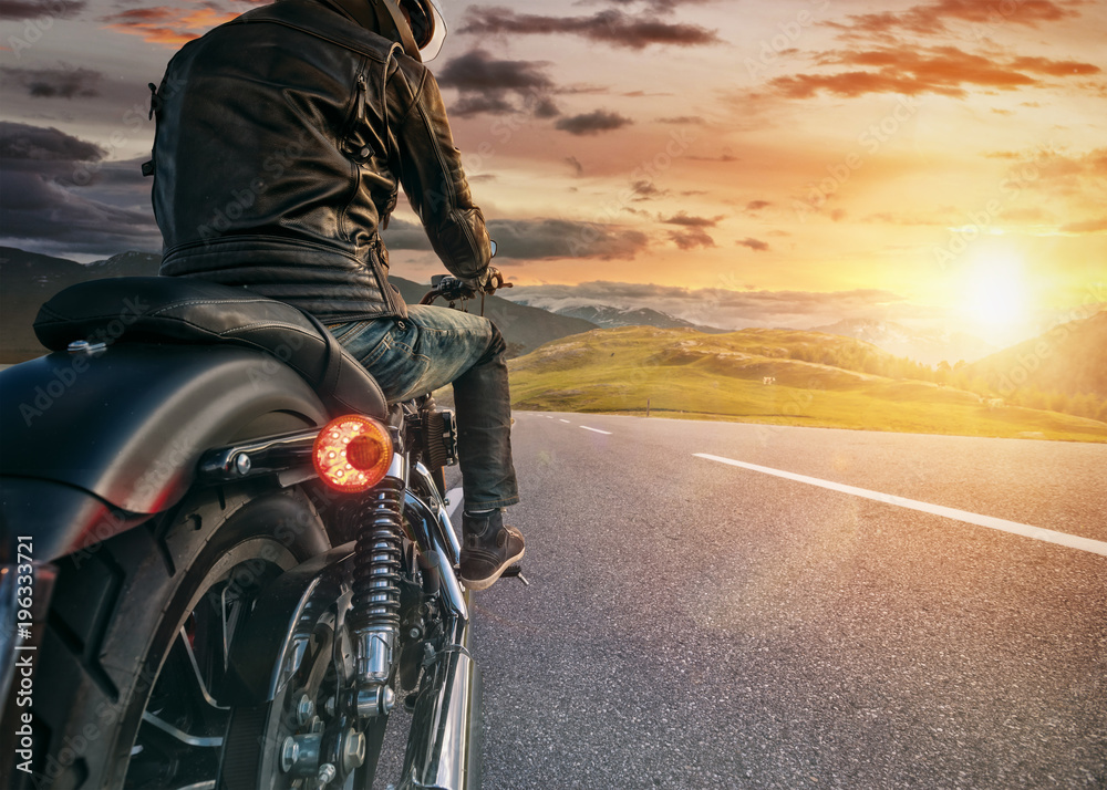 Foto de Motorcycle rider ready for drive in Alps, beautiful sunset sky ...