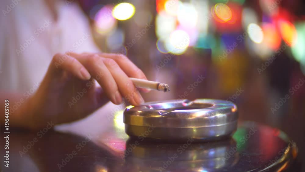 close-up, hand with a cigarette shakes ash into an ashtray. a single ...