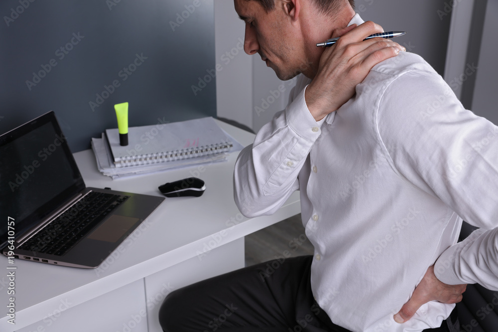 Business man suffering from back and neck pain in an office. Incorrect ...