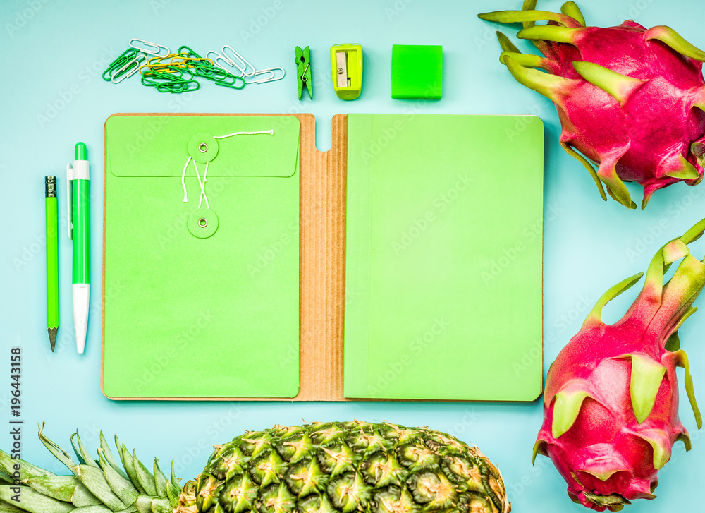 Blank green notebook with tropical fruit and accessories laying on blue ...