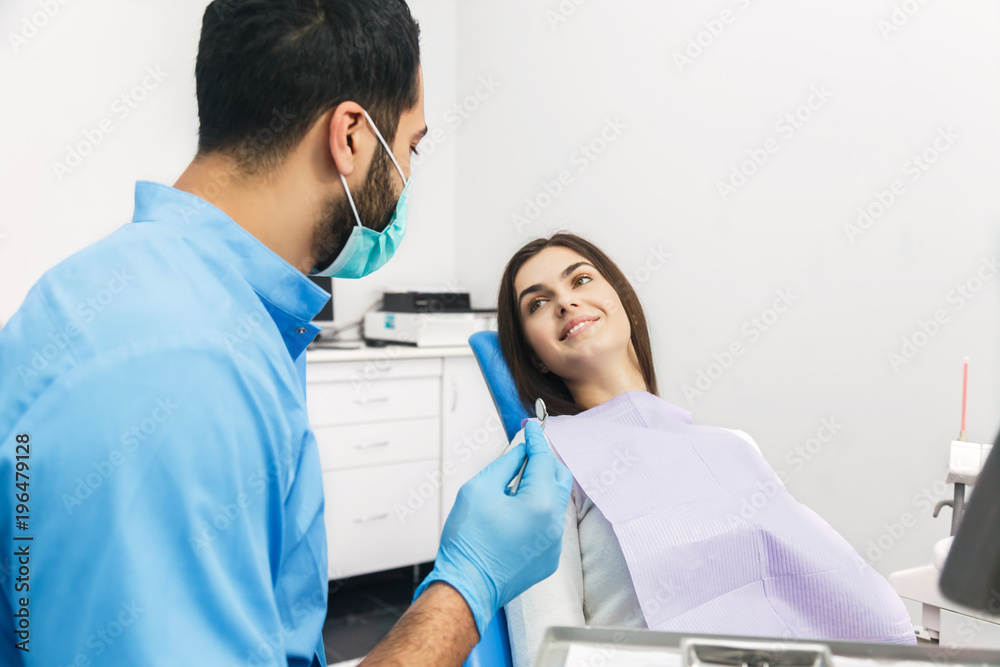 Dentist examining patient's teeth, good-looking man with black hair ...