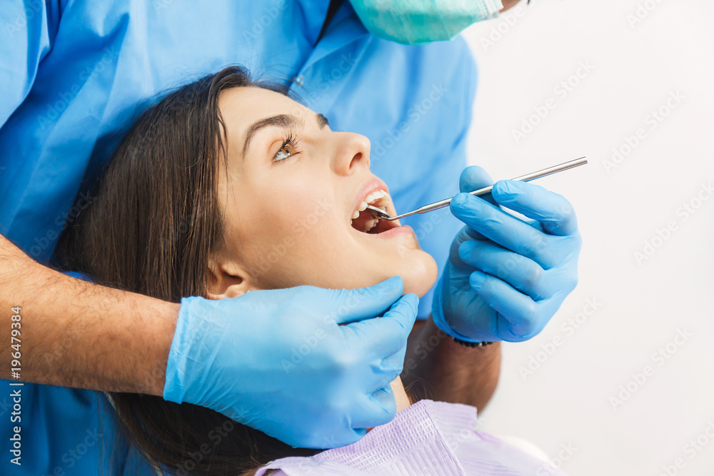 Dentist examining patient's teeth, looking at patient's teeth carefully ...