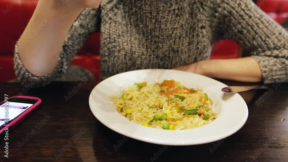 Attractive Caucasian girl eating Thai rice with vegetables in a cafe ...