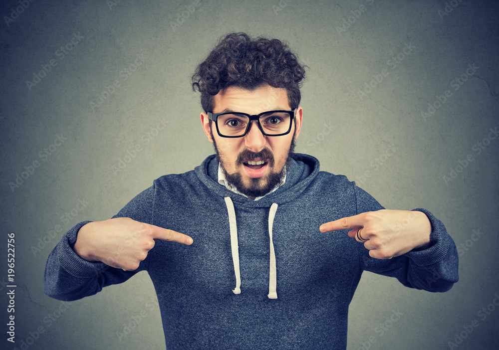 Young angry man in eyeglasses overreacting while pointing at himself ...