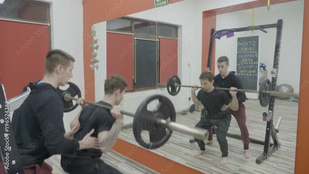 Strong male athlete lifting weights and doing squats at the same time ...