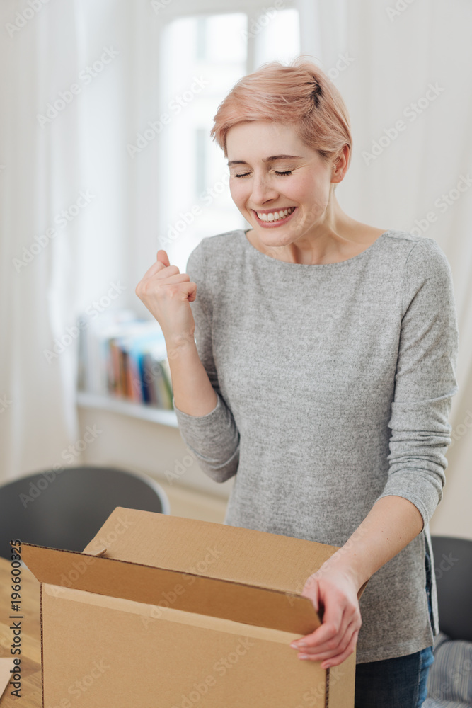Excited young woman opening a brown cardboard box Stock Photo | Adobe Stock