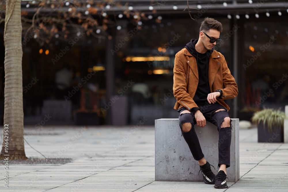 Model looking man sit on the bench in modern park background, look on ...