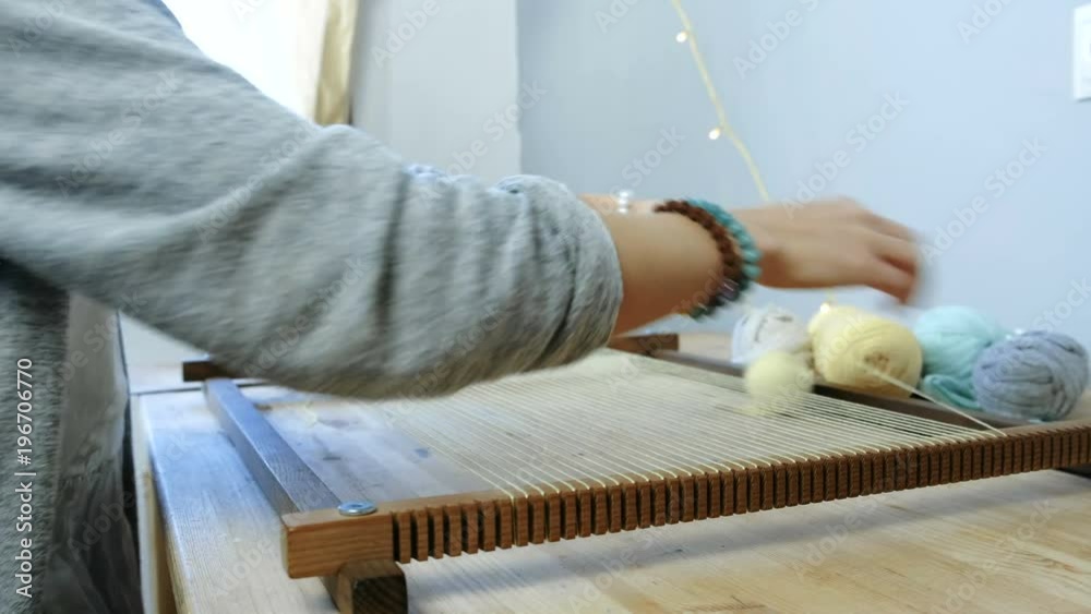 Weaving on a loom frame. Closeup woman's hand puts the thread in the ...