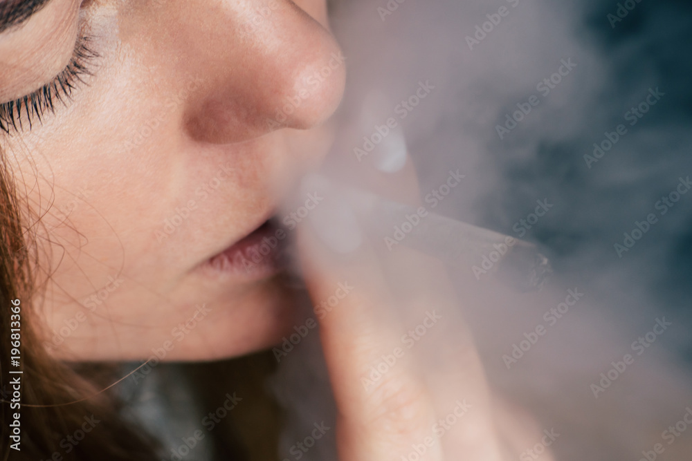 smokes cannabis weed, a joint and a lighter in his hands. Smoke on a ...