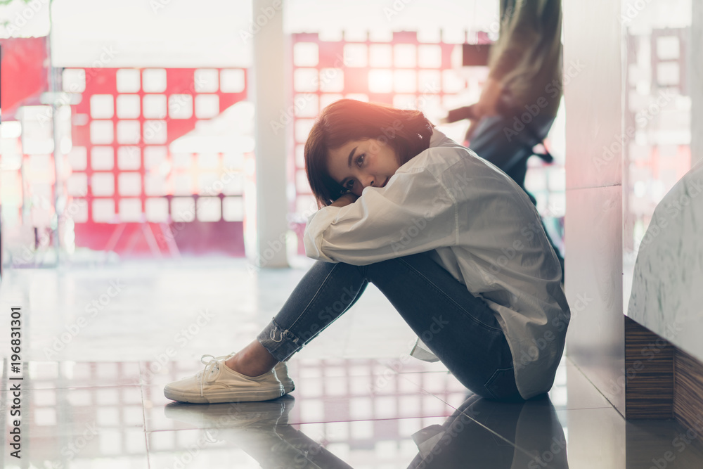Sad and depressed women sitting at walkway or office with backlit and ...