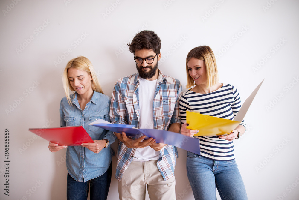 Group of young smart people leaning against the wall and looking at ...