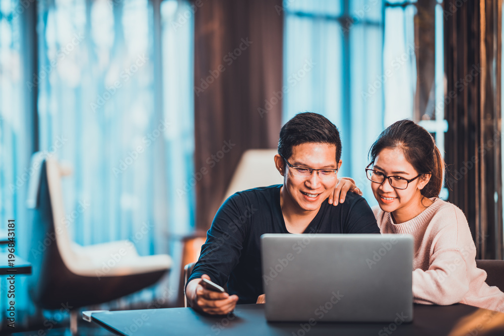 Young Asian married couple working together using laptop at home or ...