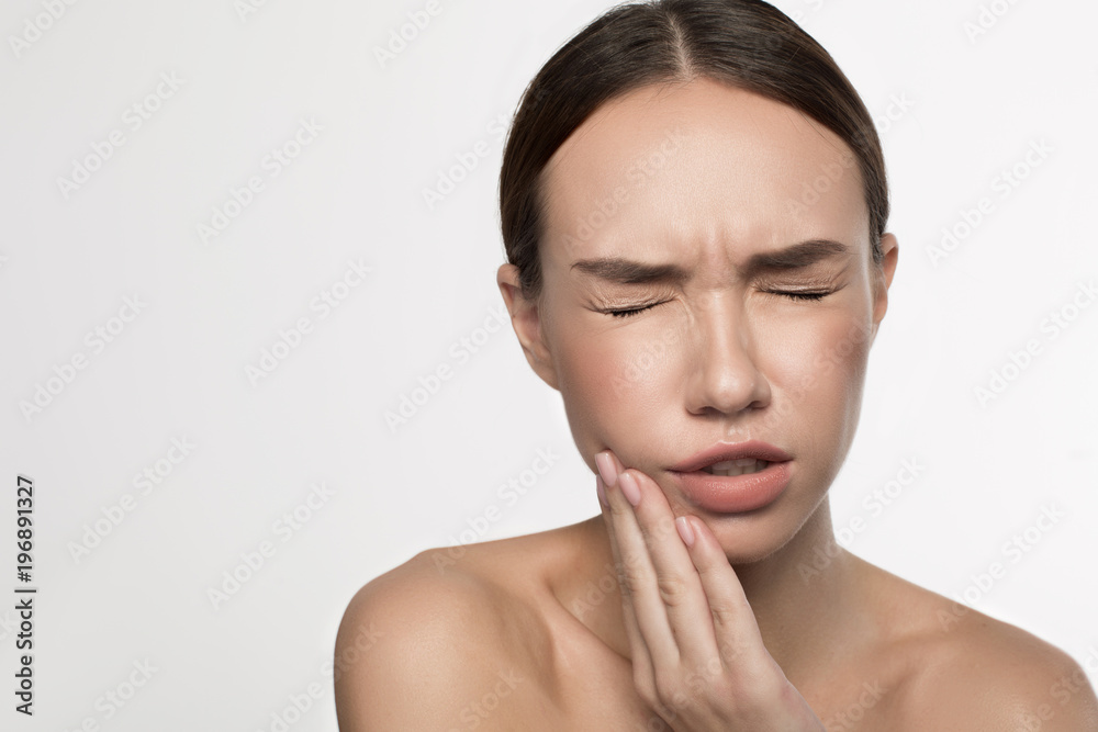 Dental pain. Portrait of joyless young woman is standing and holding ...