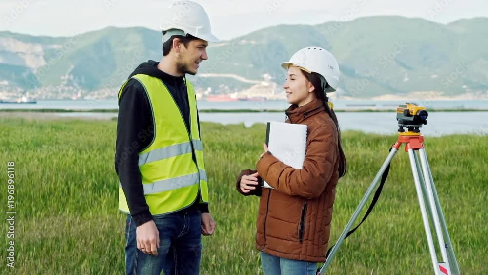 Male and female surveyors in working uniform and helmets smiling Shake ...