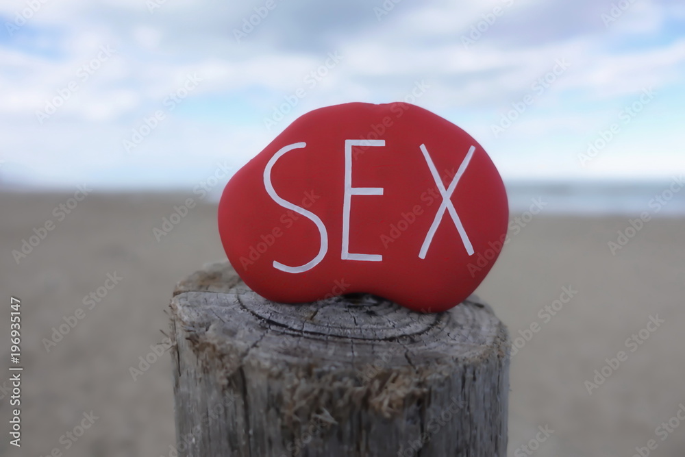 Sex Text On A Red Colored Stone On A Wooden Pole At The Beach Stock