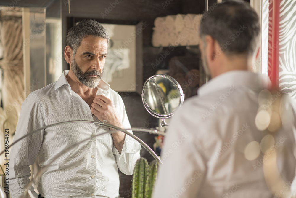 Elderly senior man checking himself out in his bathroom mirror ...