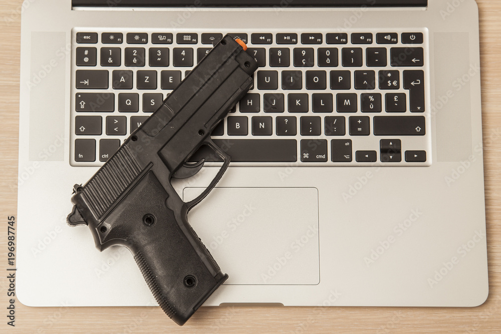 Foto de Conceptual photo, weapon on a laptop as a symbol of organized ...