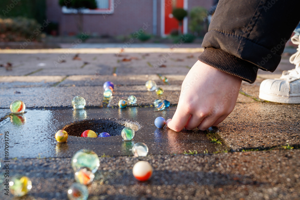 Child playing with marbles on yhe sidewalk. old-fashioned toys still in ...