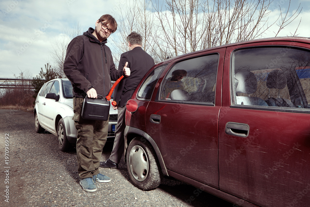 Car driver filling empty tank from colleagues reserve canister Stock ...
