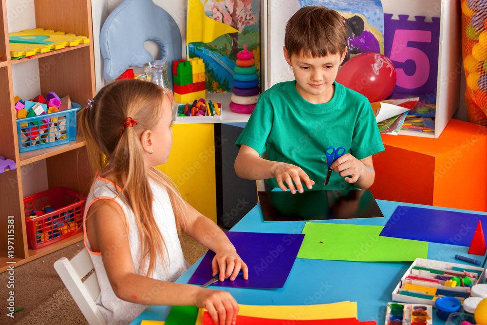 School children with scissors in kids hands cutting paper with teacher ...