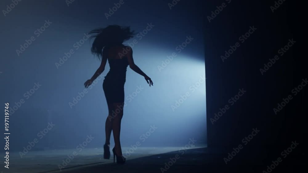 Beautiful dancer demonstrating her perfect sensual figure and dancing on dark blue background ...