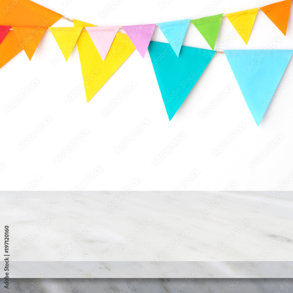 Colorful party flags hanging on white wall and white marble table ...