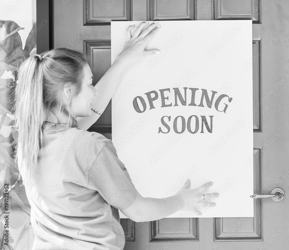 Woman putting on store opening soon sign Stock Photo | Adobe Stock
