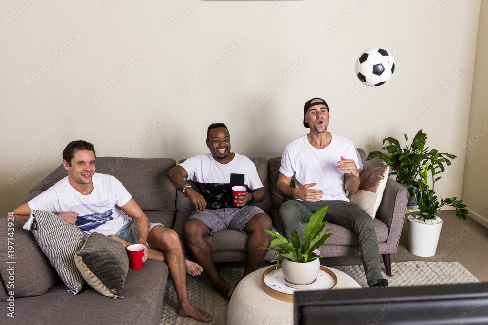Group of multinational guys watching football on TV with excitement ...