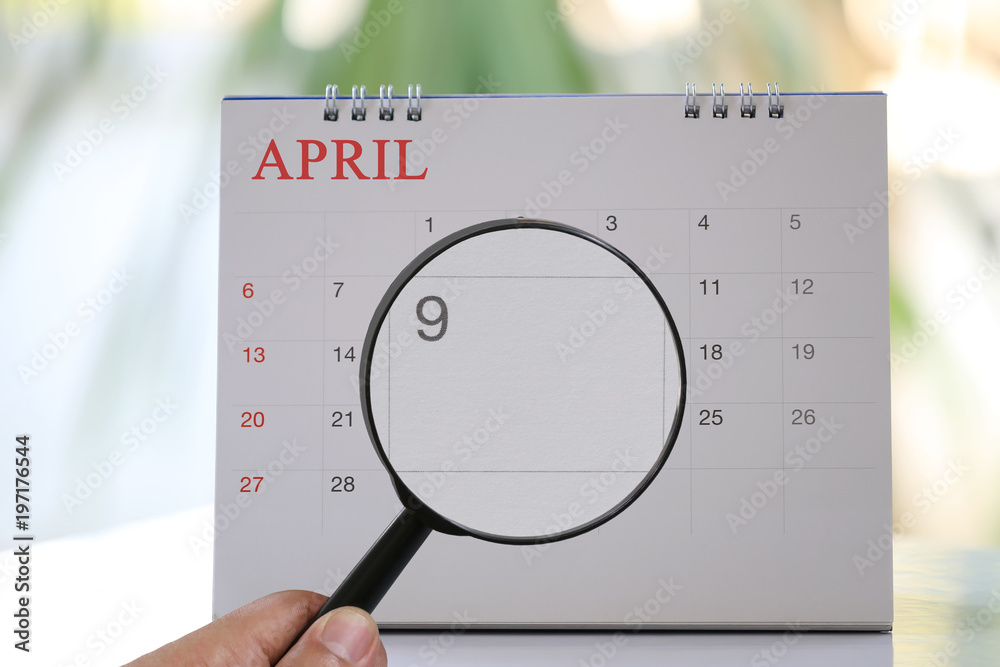 Magnifying glass in hand on calendar you can look ninth day of month ...