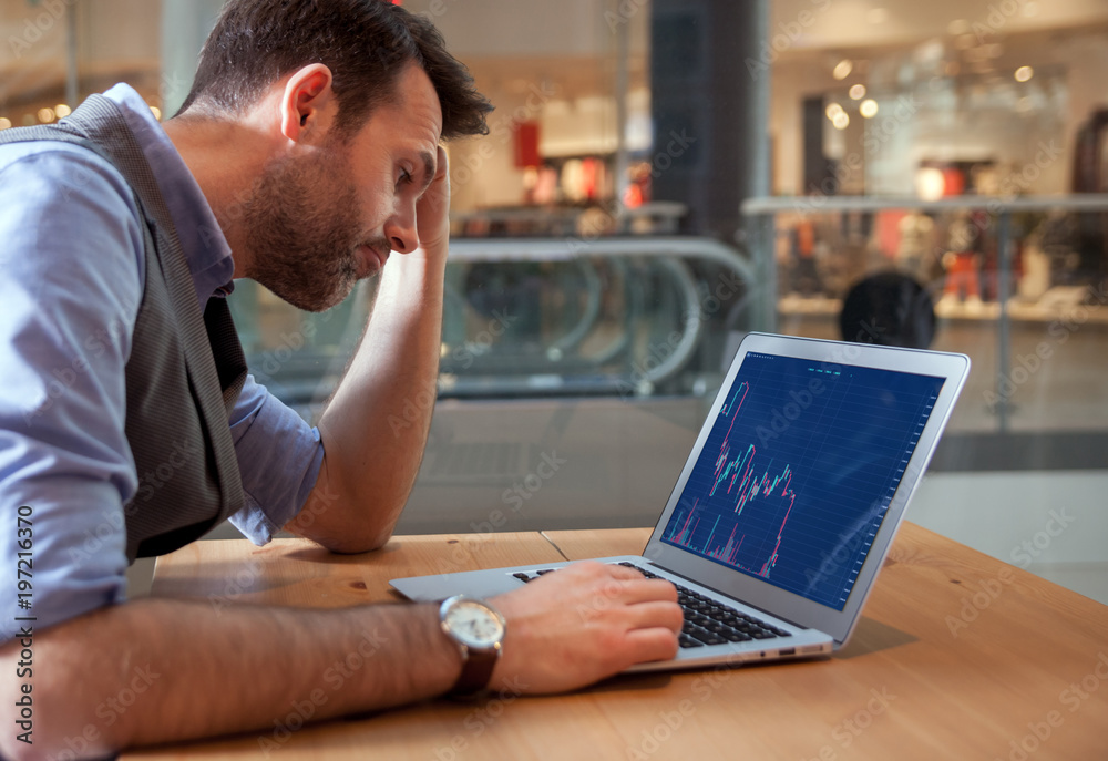 Depressed investor analyzing crisis stock market with charts on screen ...