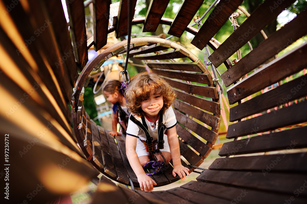 children - a boy and a girl in the rope park pass obstacles. Brother ...