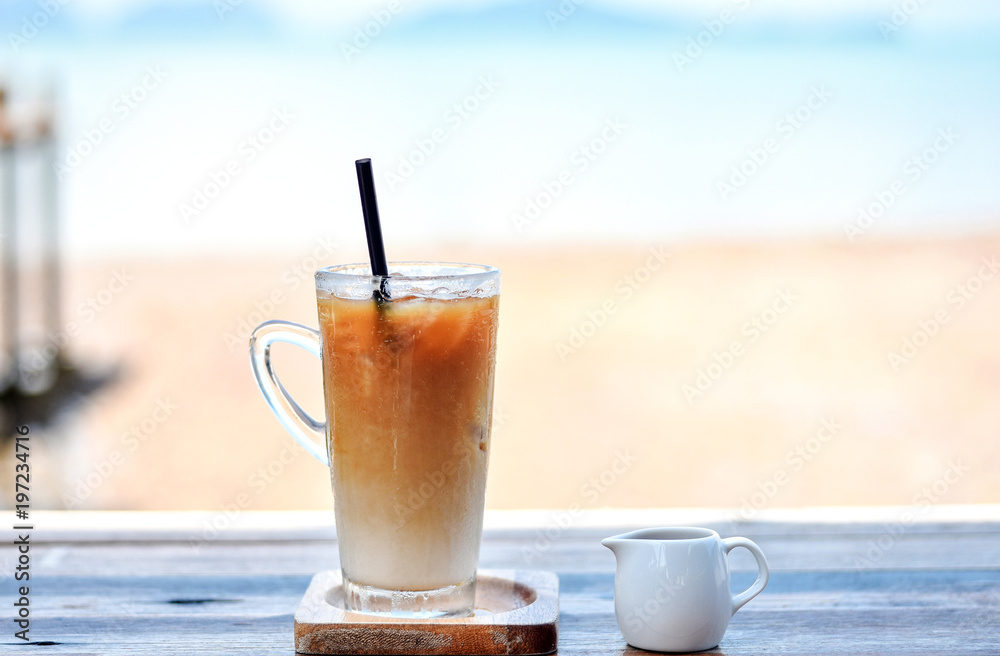 Iced cold coffee glass at the beach bar with blurred seascape in the ...
