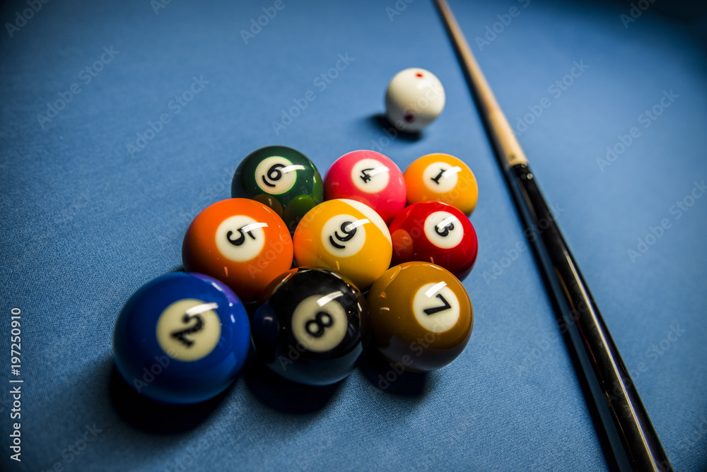 A rack of 9 ball with cue ball and a billiard cue on a blue texture ...