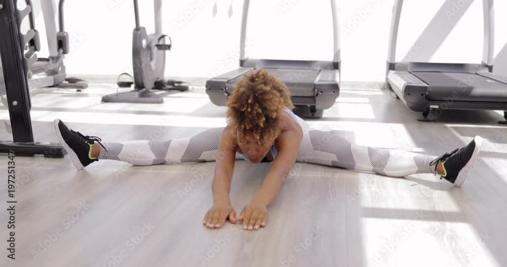 Pretty sportive woman in stylish sportswear doing splits on floor of ...