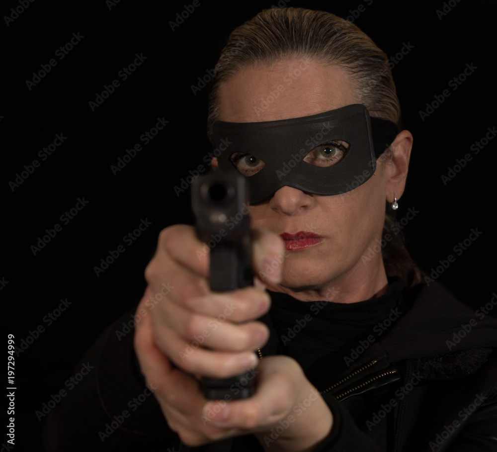 masked woman with gun is serious and pointing it at you Stock Photo ...