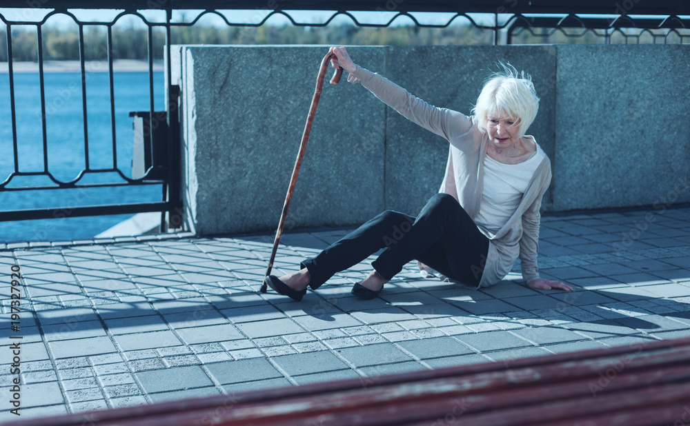 Oh no. Frightened retired woman leaning on a walking cane while trying ...