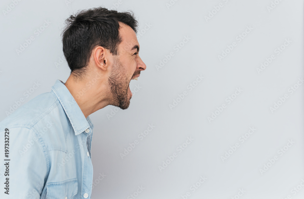 Side view portrait of emotional mad stylish young male screams loudly ...